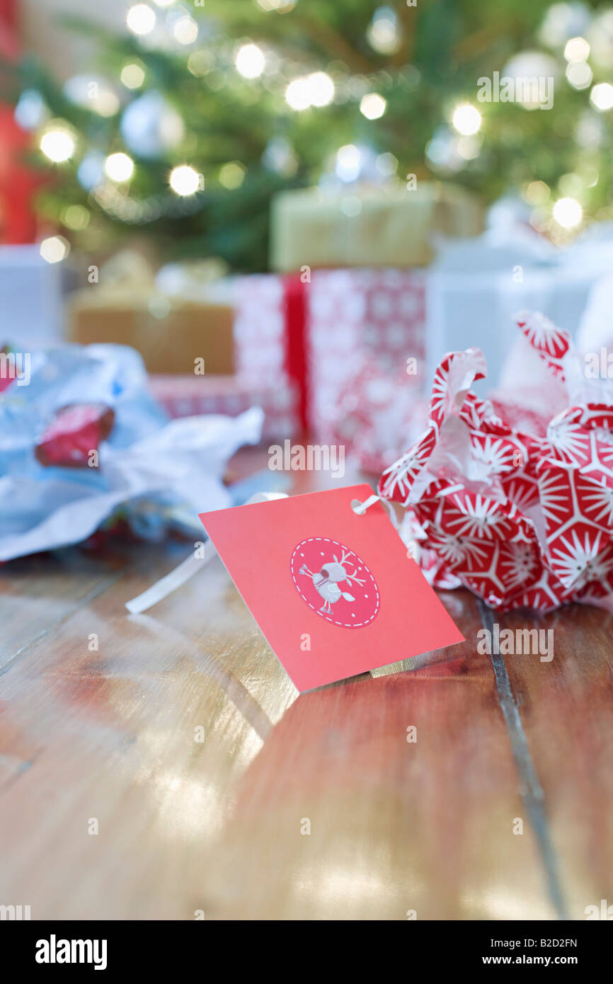 Gifts, unwrapped paper and gift tag on floor Stock Photo - Alamy