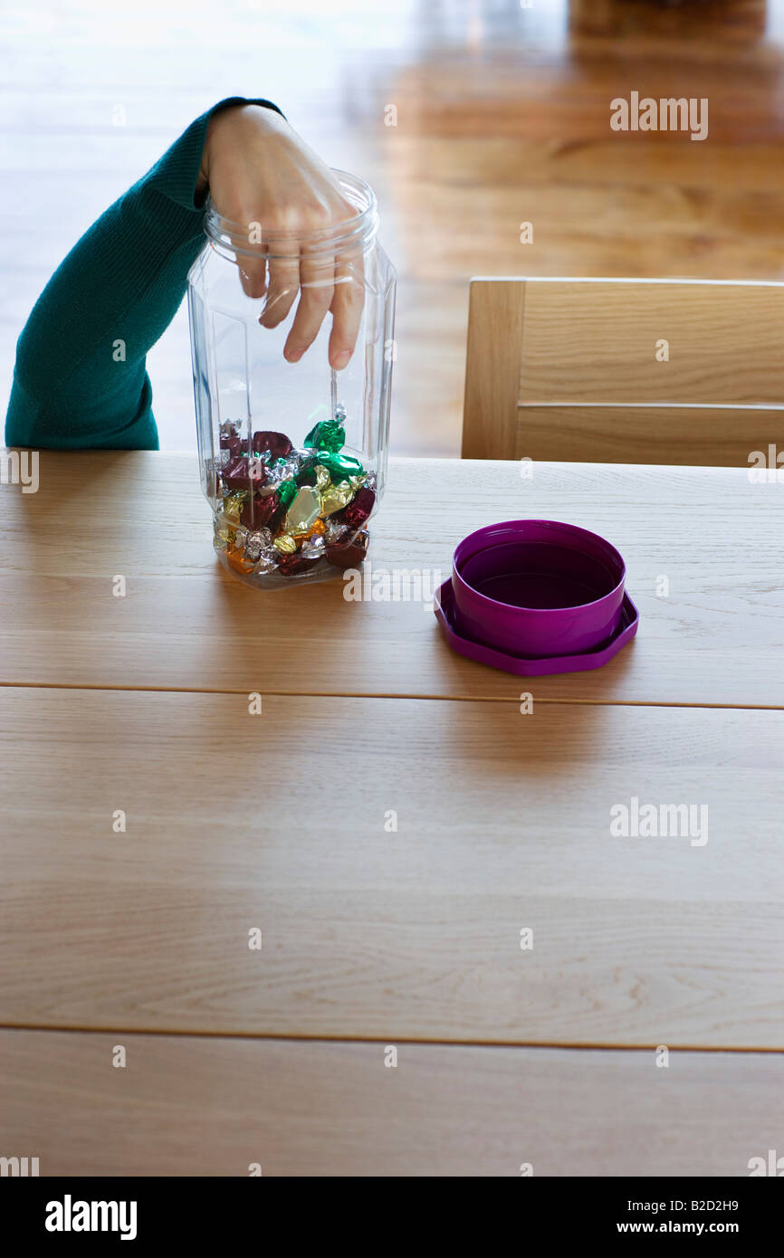 Hand of child taking candies from jar Stock Photo - Alamy