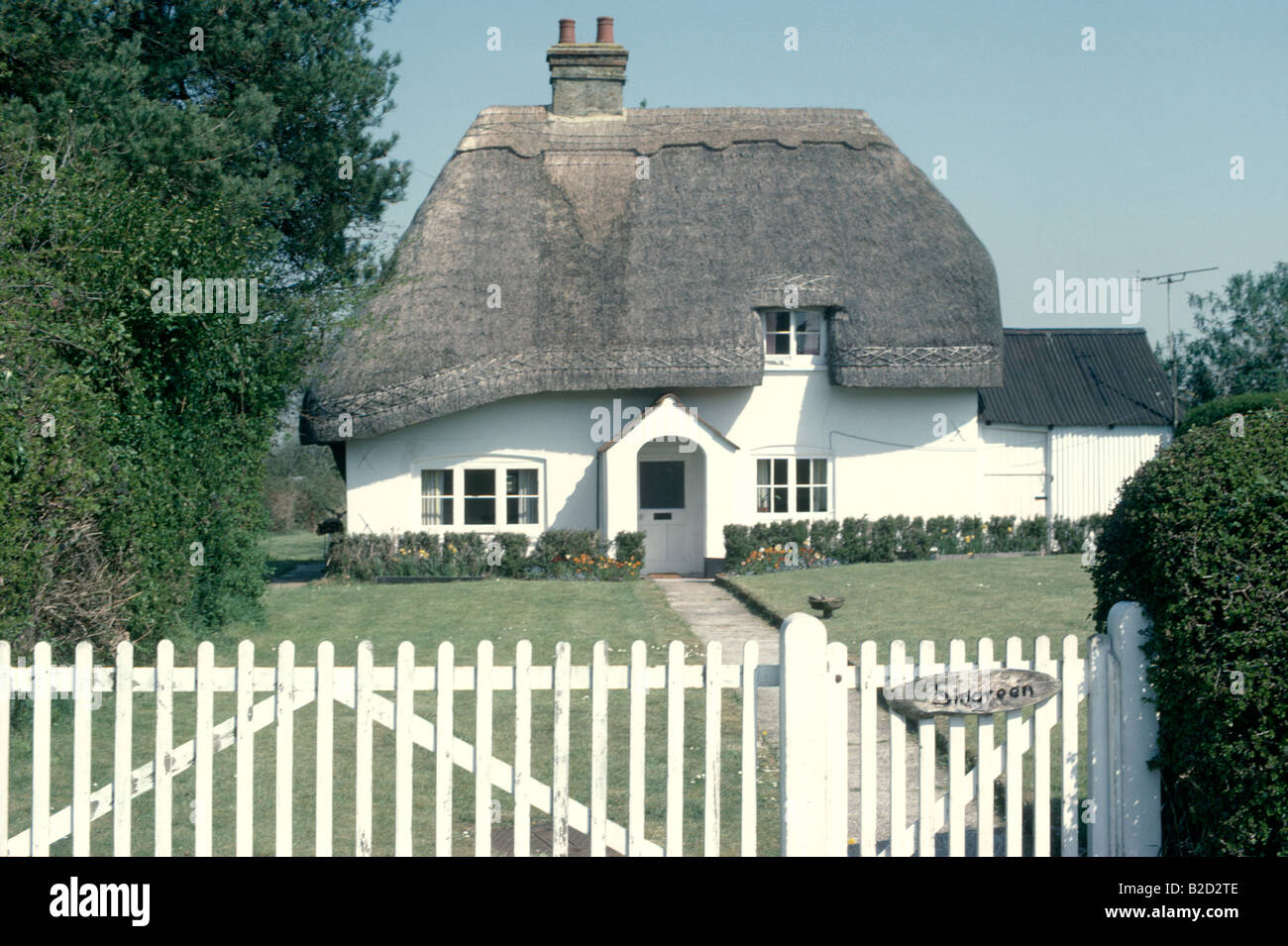 White picket fence and gate in front of small white country cottage ...