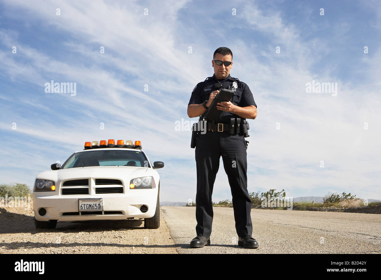 Police officer taking notes in front of police car Stock Photo - Alamy