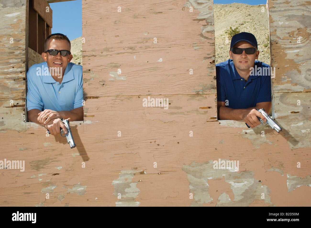 Two men holding hand guns at firing range, portrait Stock Photo - Alamy