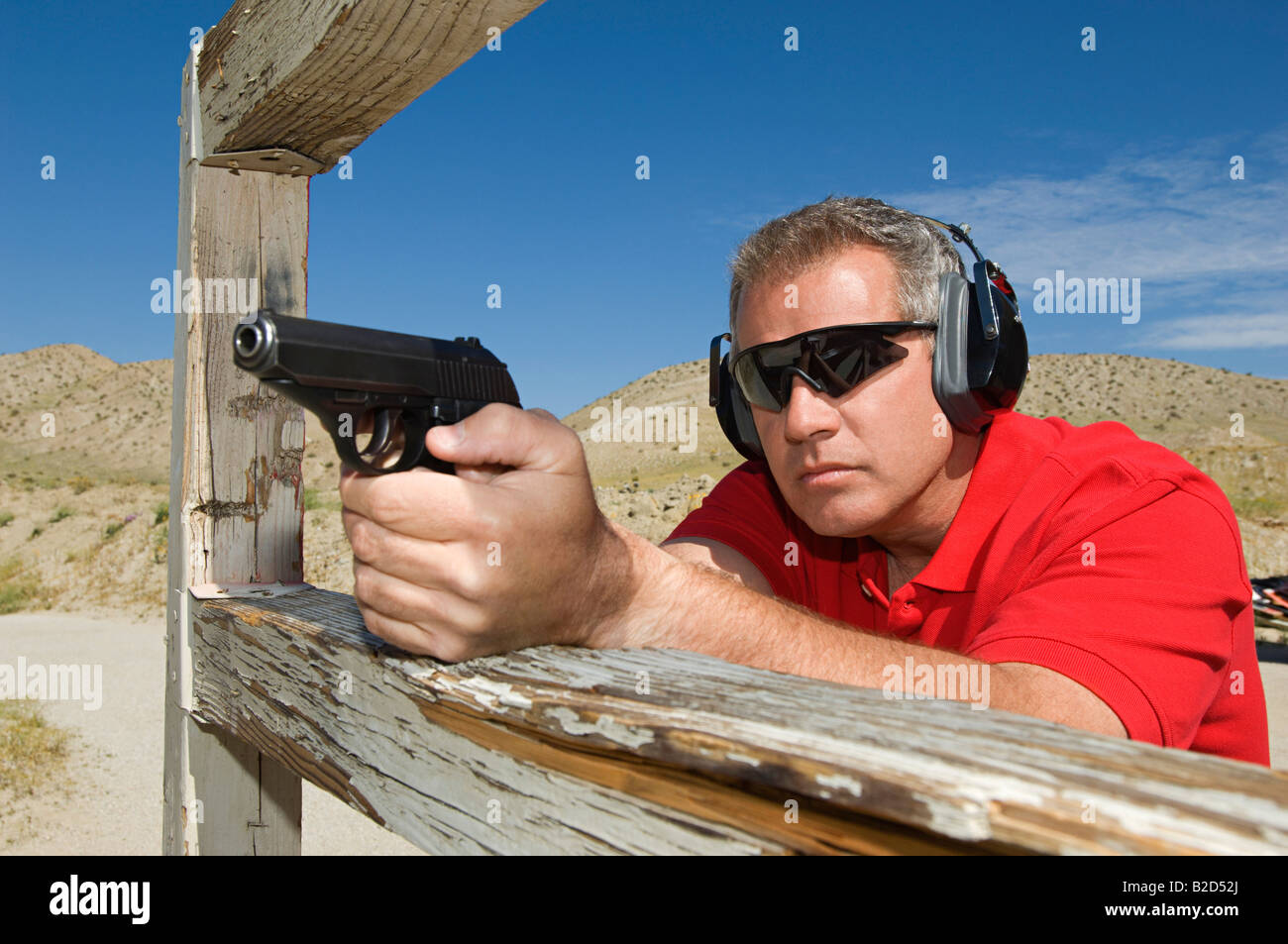 Man aiming hand gun at firing range Stock Photo - Alamy