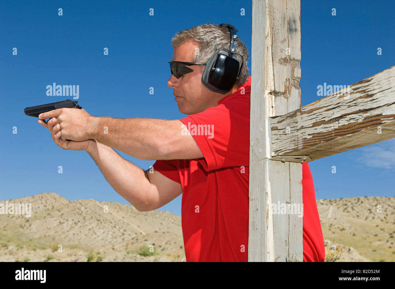 Man aiming hand gun at firing range Stock Photo - Alamy