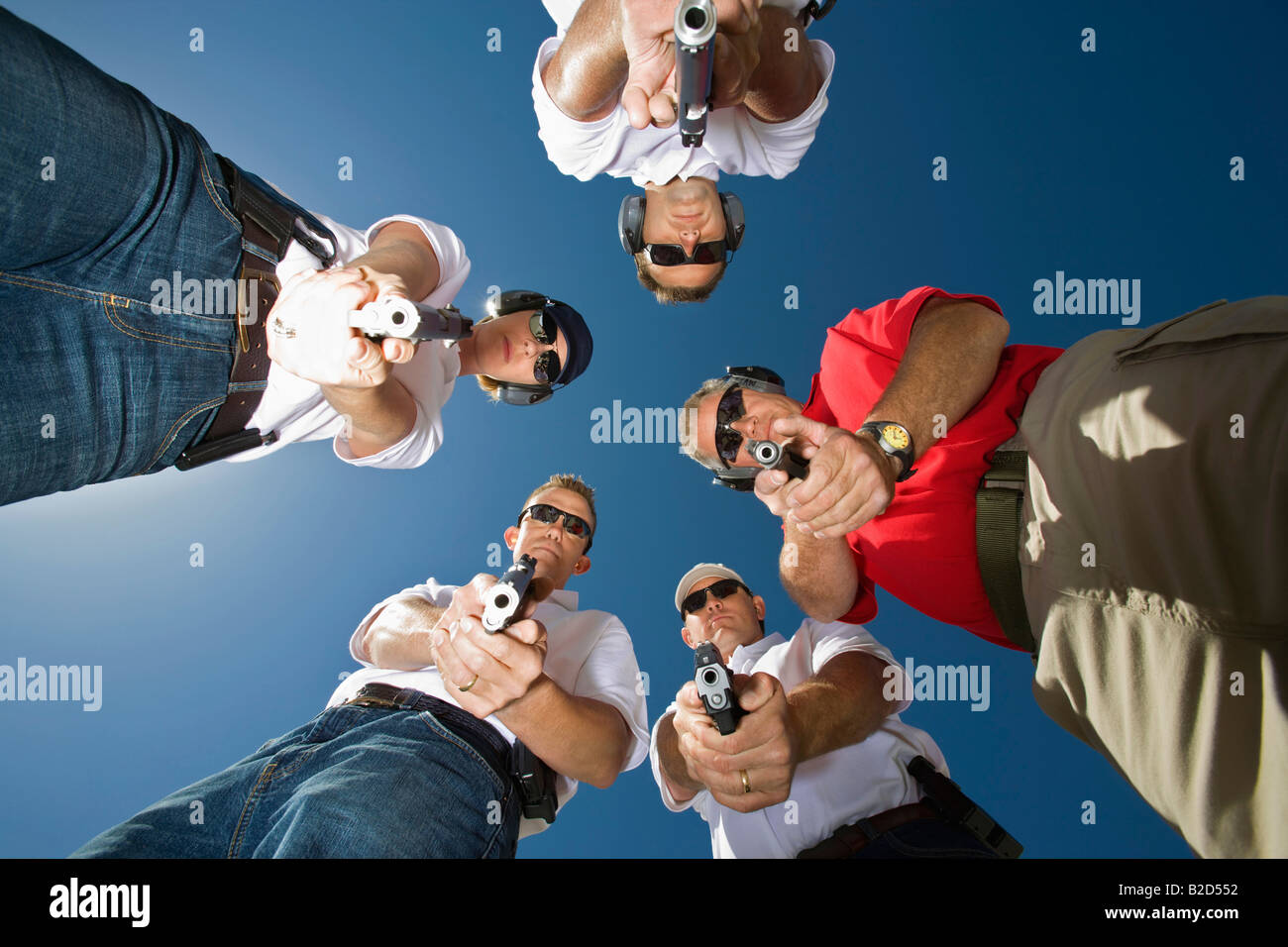 Group of people aiming guns in circle, low angle view Stock Photo - Alamy