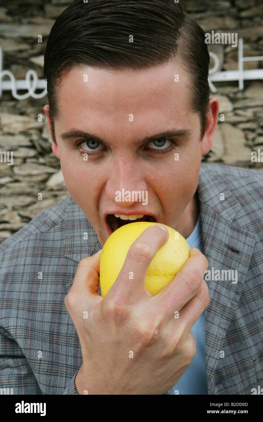 Young retro man biting into lemon Stock Photo - Alamy