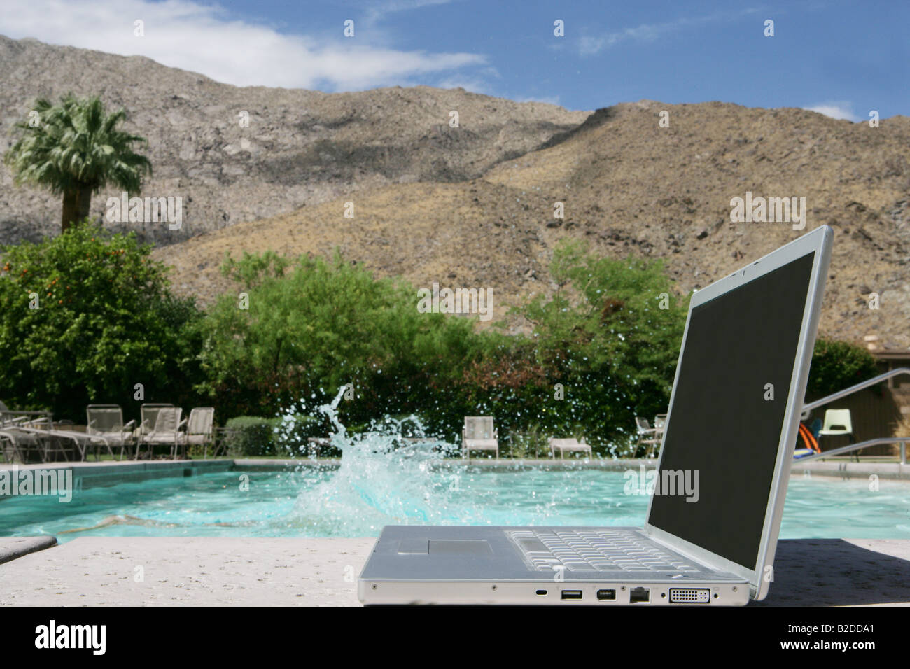 Laptop near swimming pool with water splashing Stock Photo - Alamy