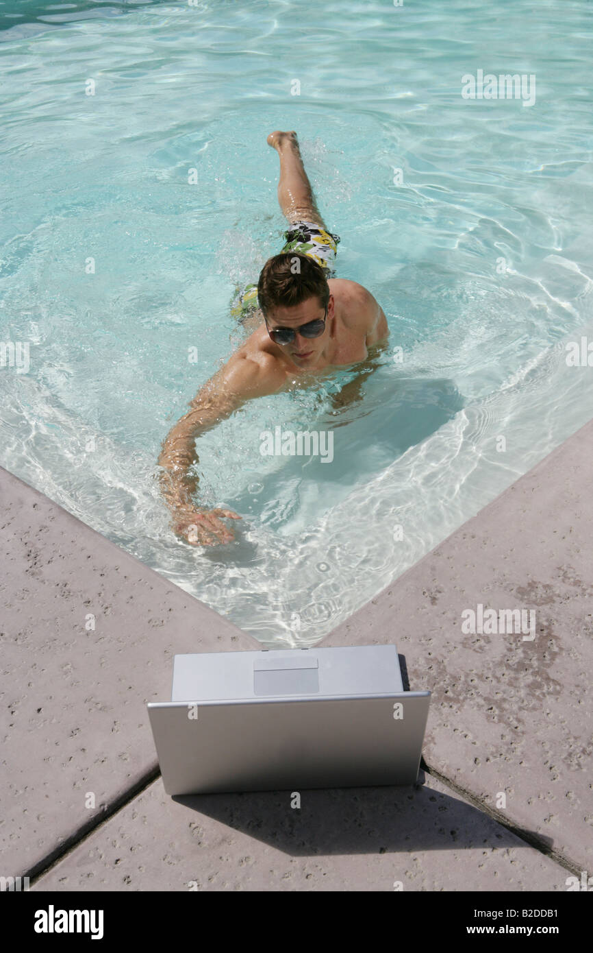 Laptop near pool with man swimming Stock Photo - Alamy