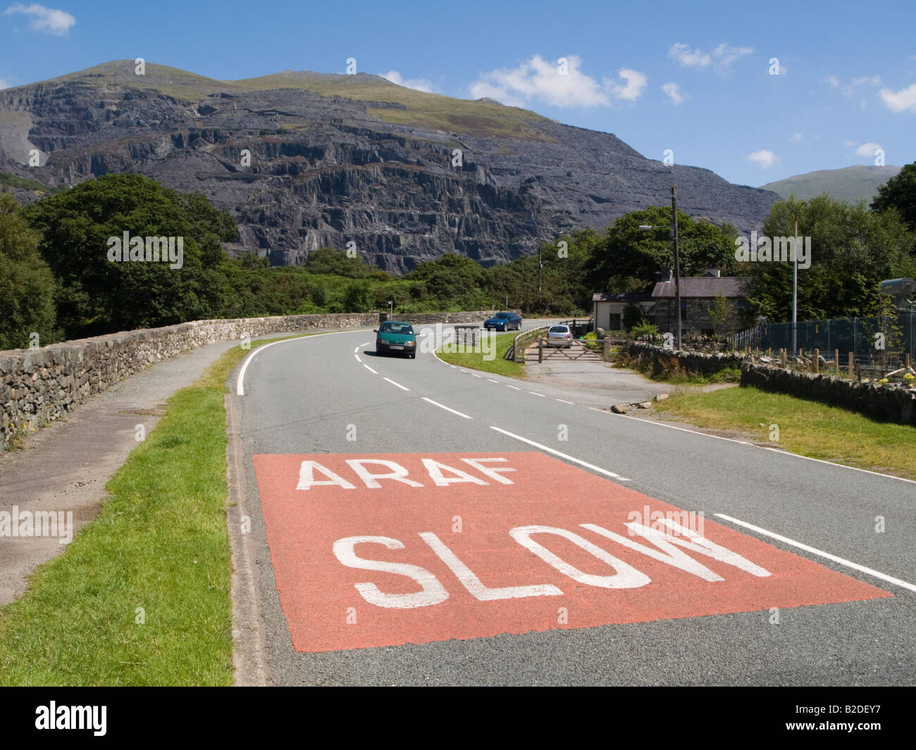 Bilingual Araf Slow sign in Welsh and English painted on a road surface ...