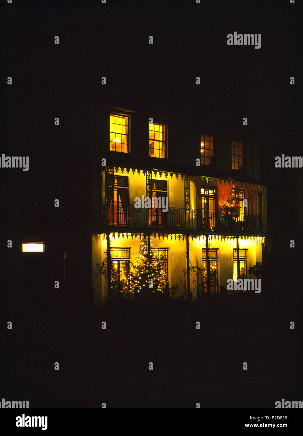 Traditional house lit at night with Christmas tree below balcony Stock ...