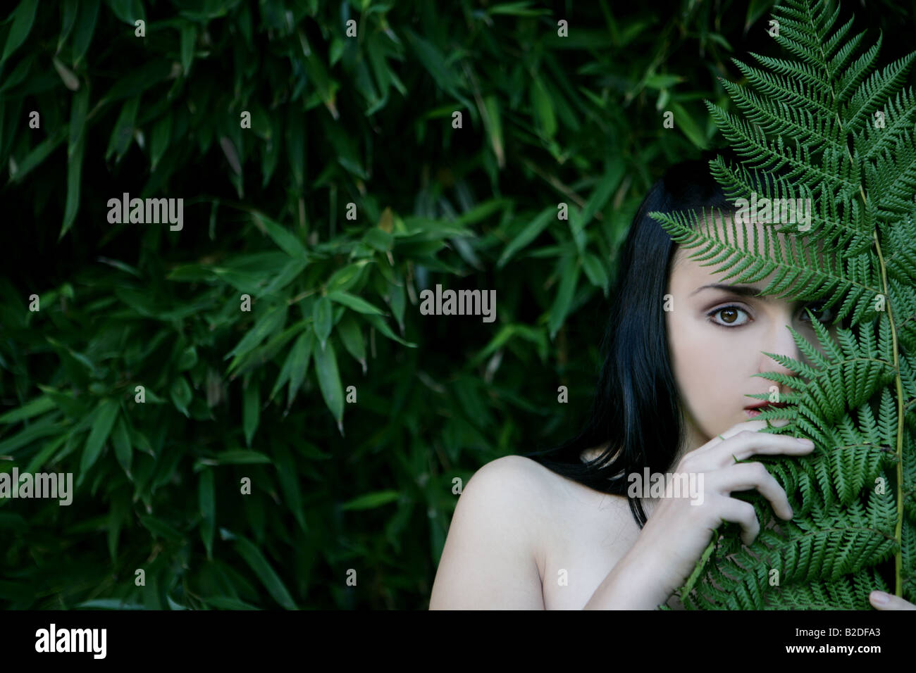 Young woman hiding behind leaves Stock Photo - Alamy