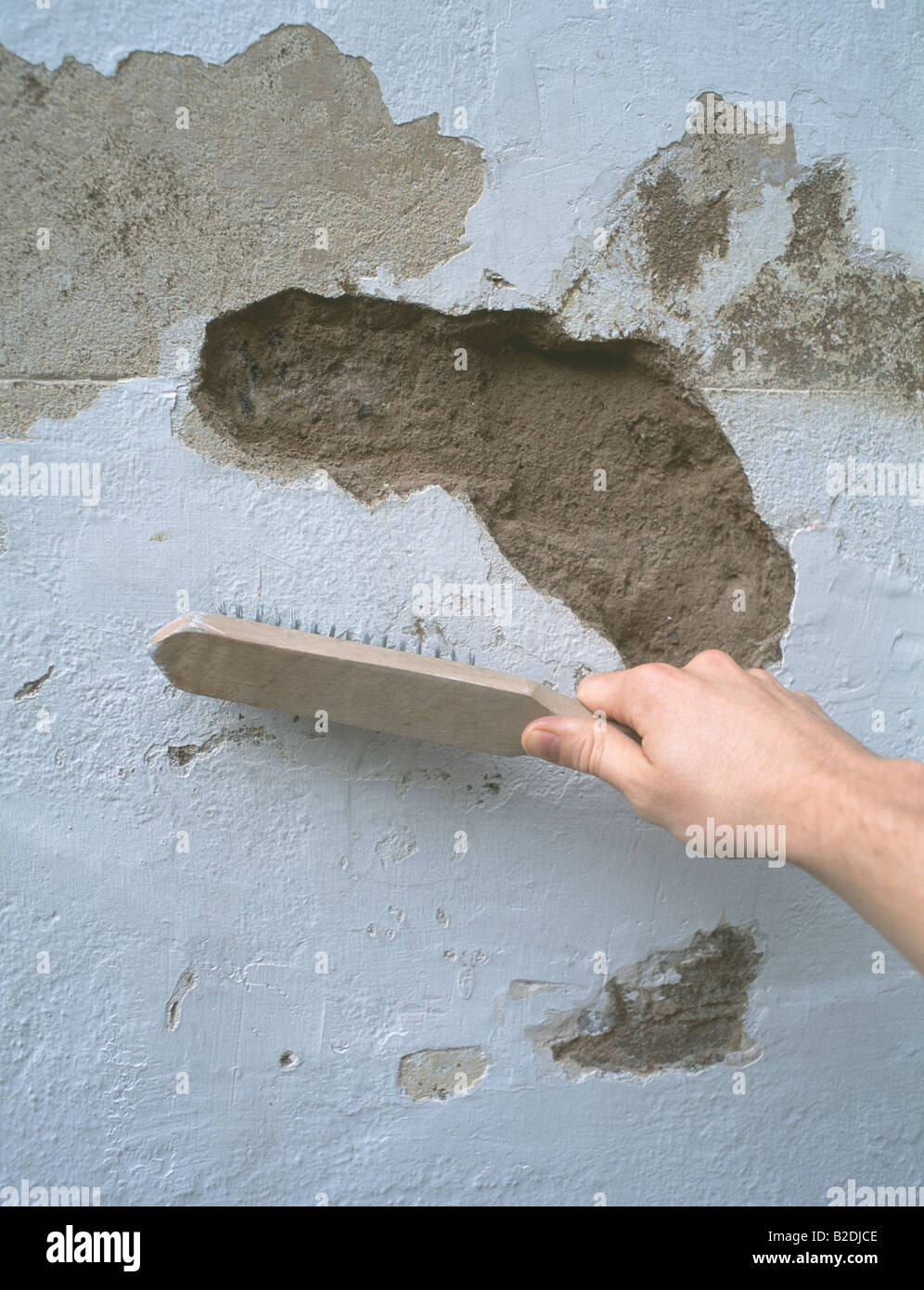 Close-up of hand using brush on damaged plaster wall Stock Photo - Alamy