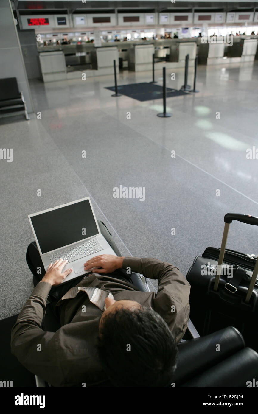 Young businessman using laptop in airport Stock Photo - Alamy