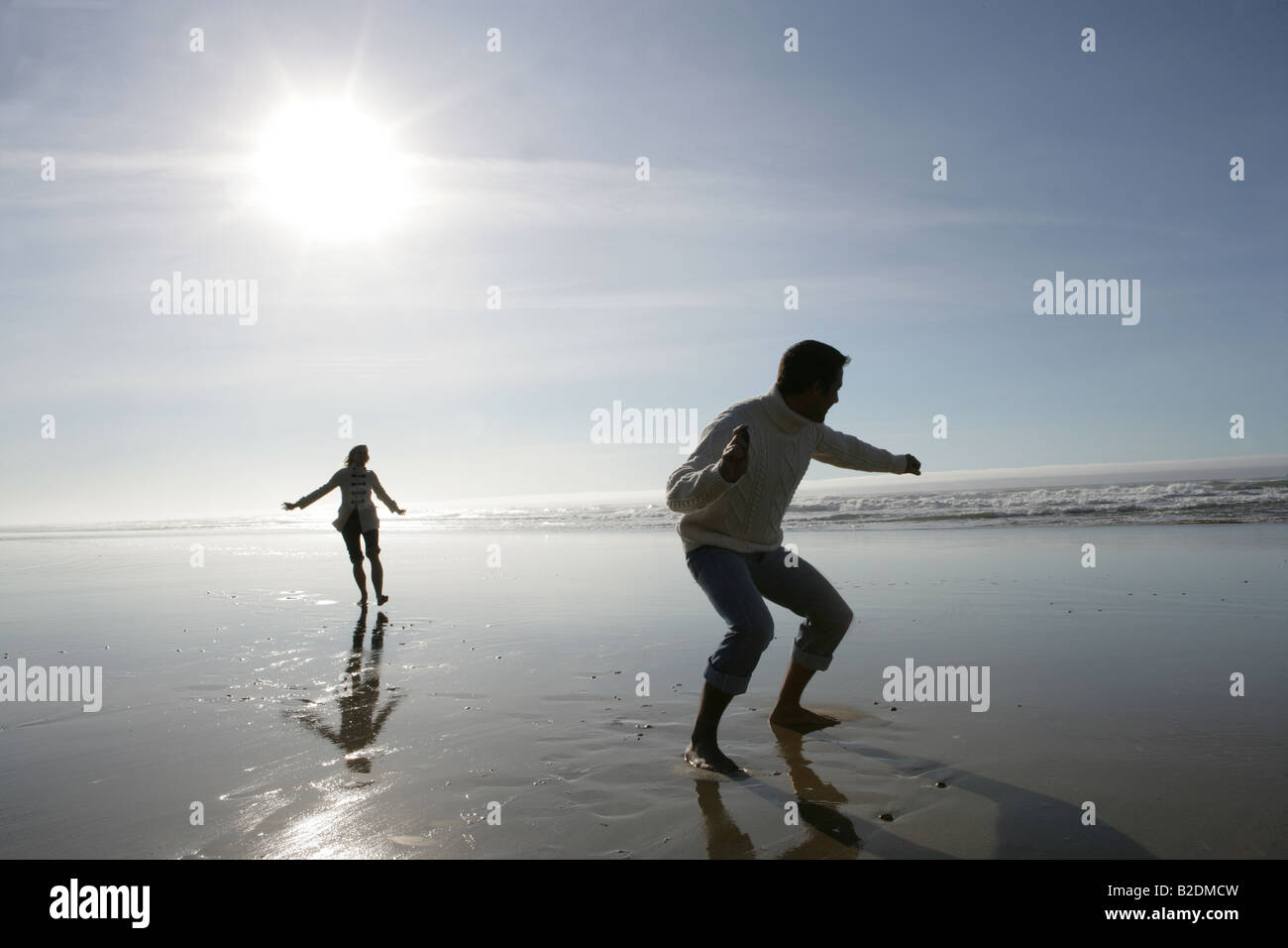 Young couple skipping rocks at beach Stock Photo - Alamy