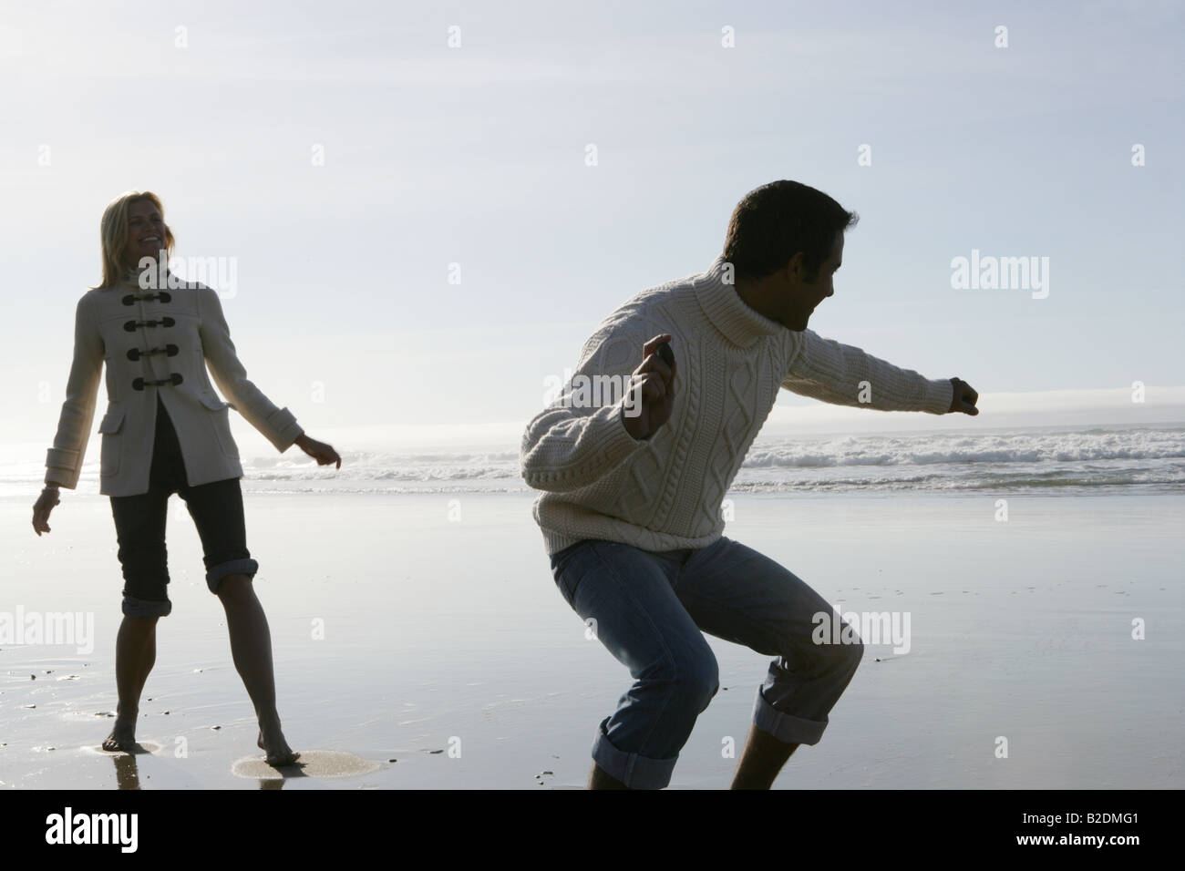 Young couple skipping rocks at beach Stock Photo - Alamy