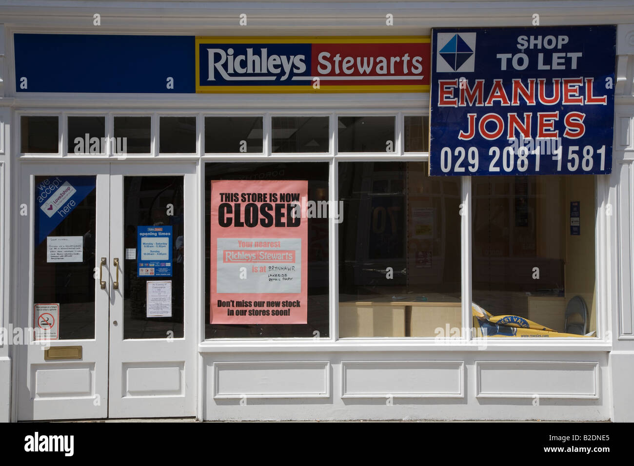 Closed shop with posters in window and for sale sign plus notice that ...