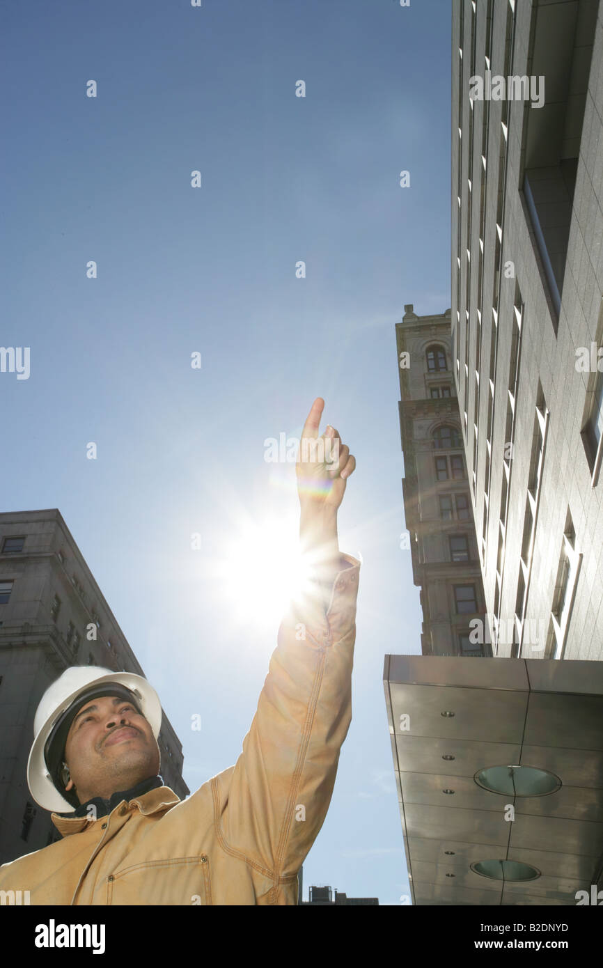 Male construction worker pointing to building Stock Photo - Alamy