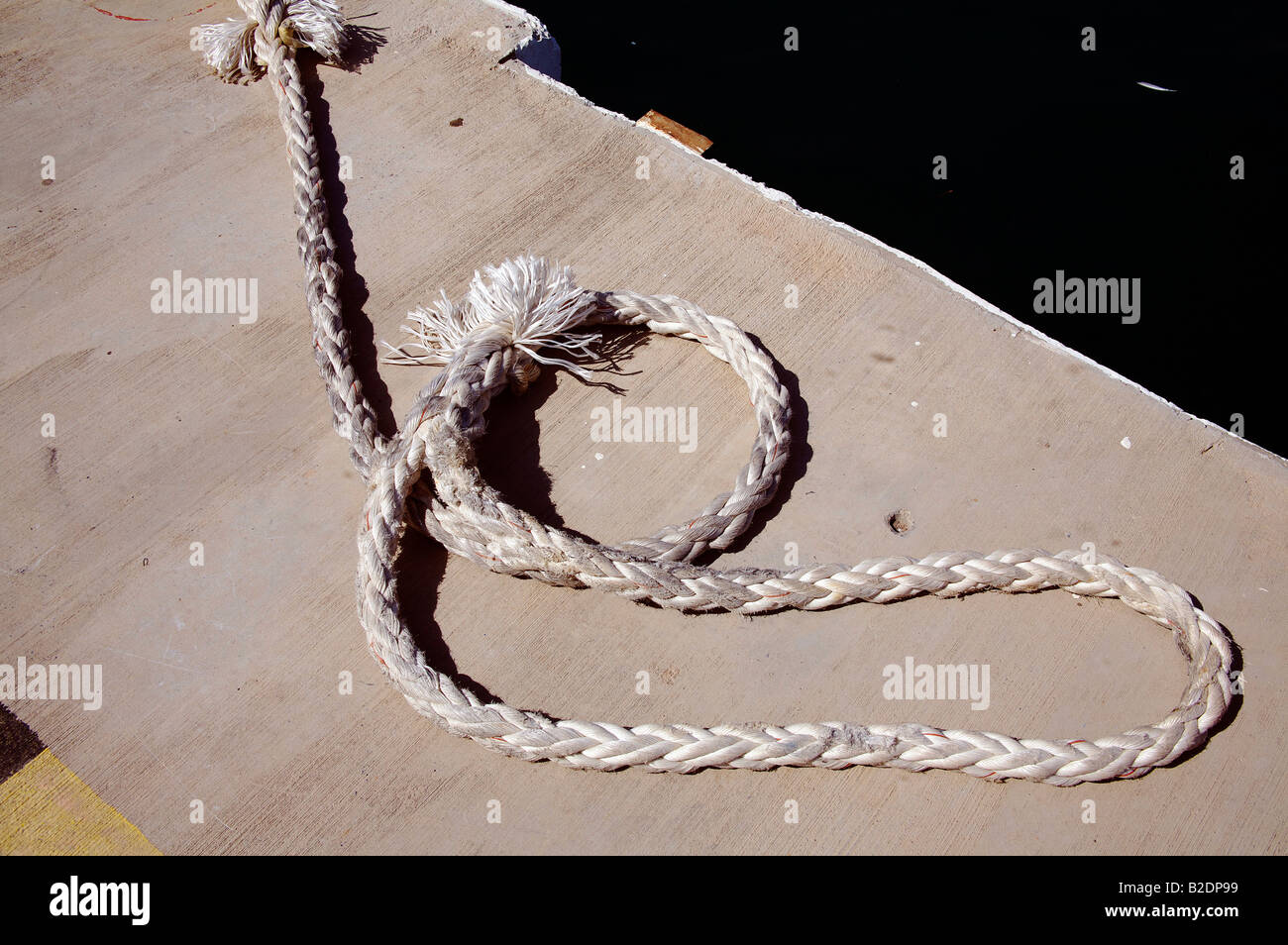 thick rope coiled on a cement dock Stock Photo - Alamy