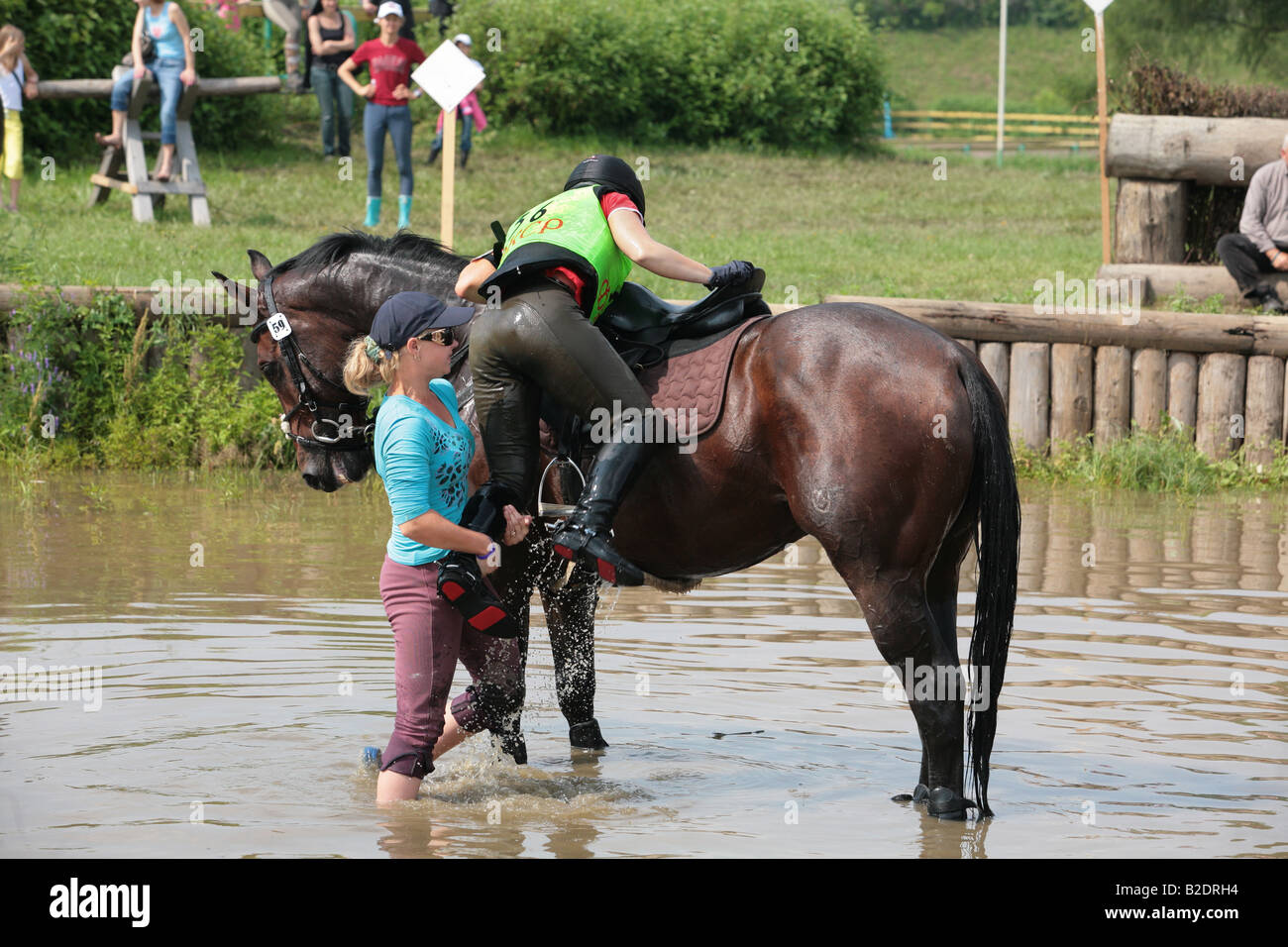 The girl-groom helps the fallen rider to sit in a saddle Stock Photo ...
