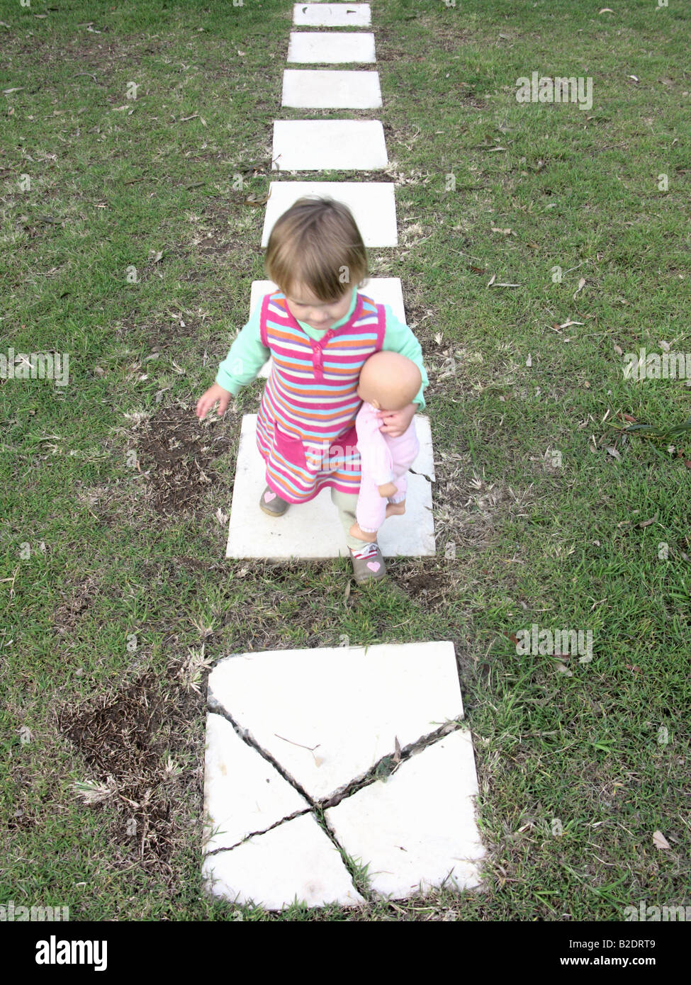 Child Girl holding doll walking on path Stock Photo - Alamy