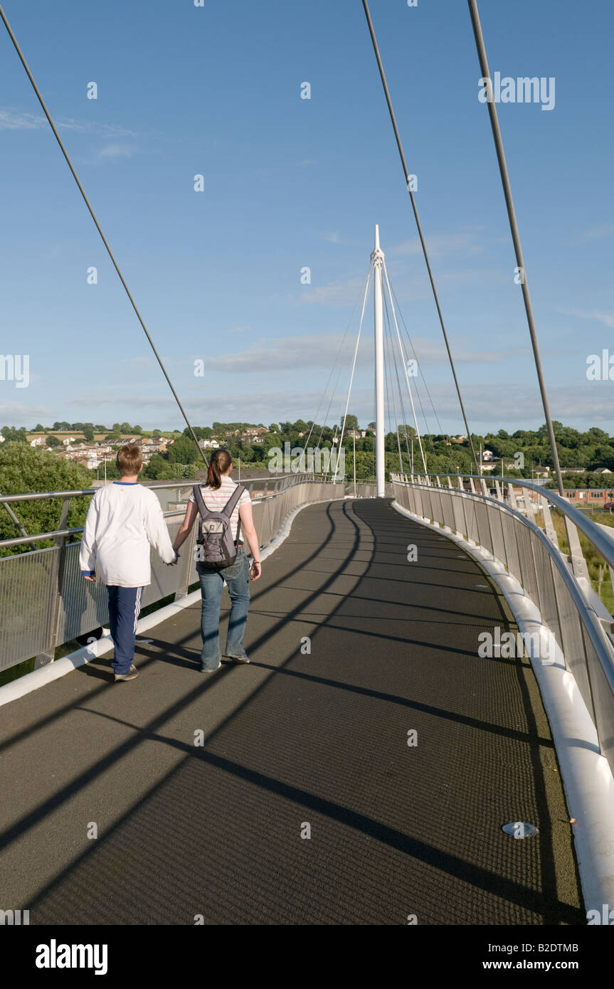 Two people crossing the Pont King Morgan suspension footbridge over the ...