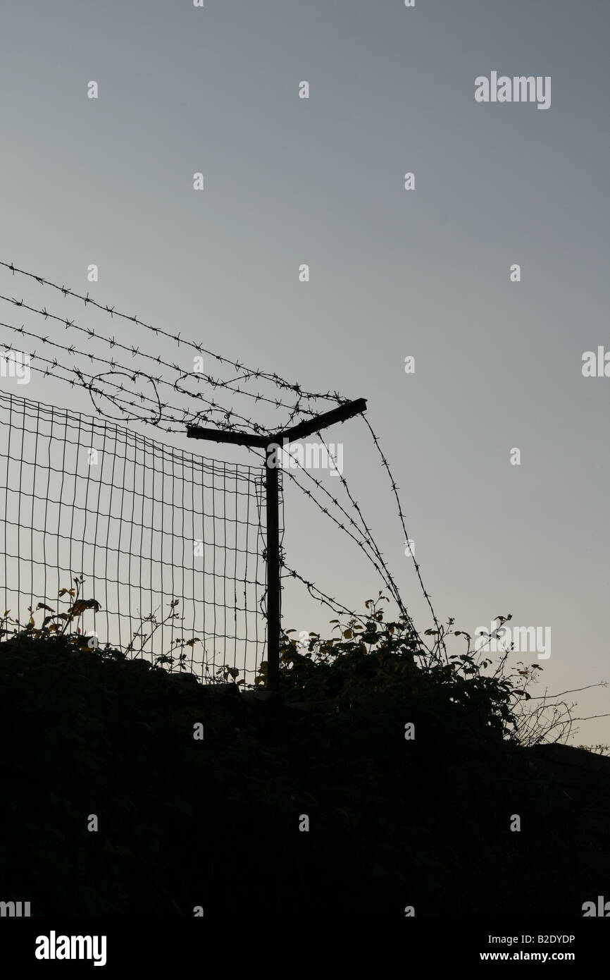 high wall fence with barbed wire outdoors at night Stock Photo - Alamy