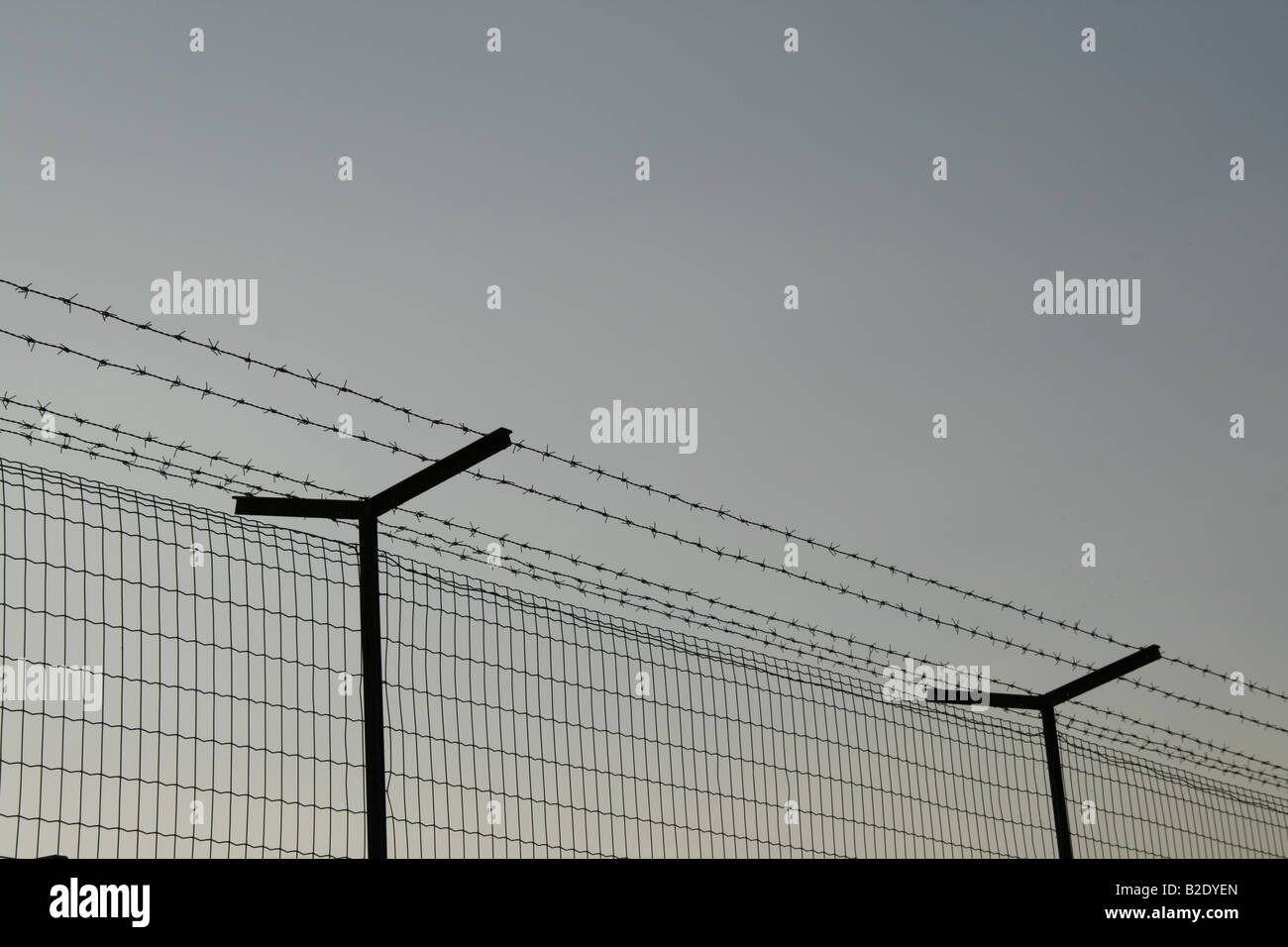 high wall fence with barbed wire outdoors at night Stock Photo - Alamy