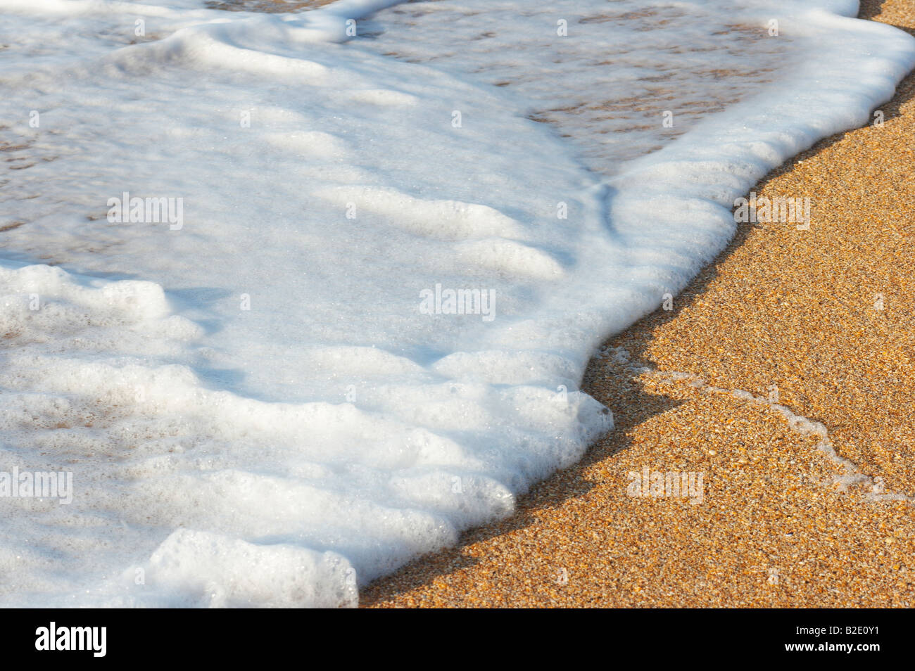 Sea surf foam on coastline sand Stock Photo - Alamy