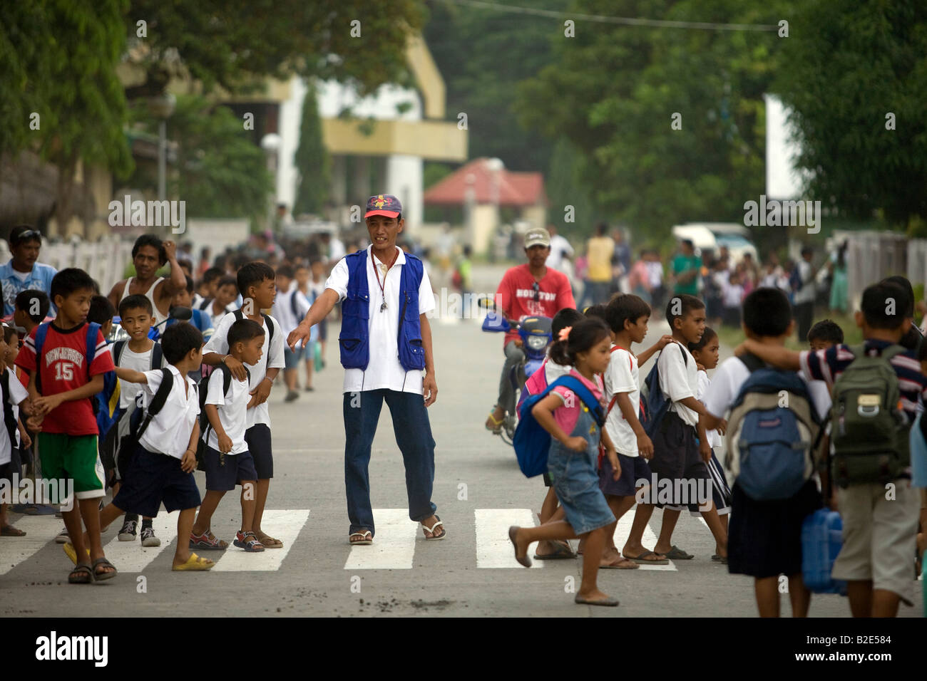 A crossing guard directs children across a street after school in ...