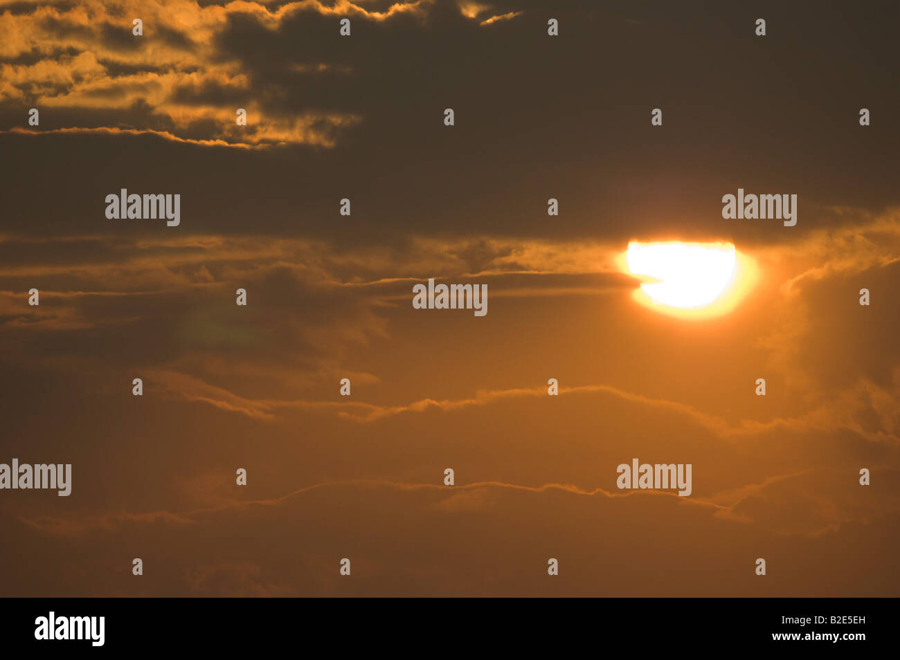 Sun setting behind clouds Stock Photo - Alamy