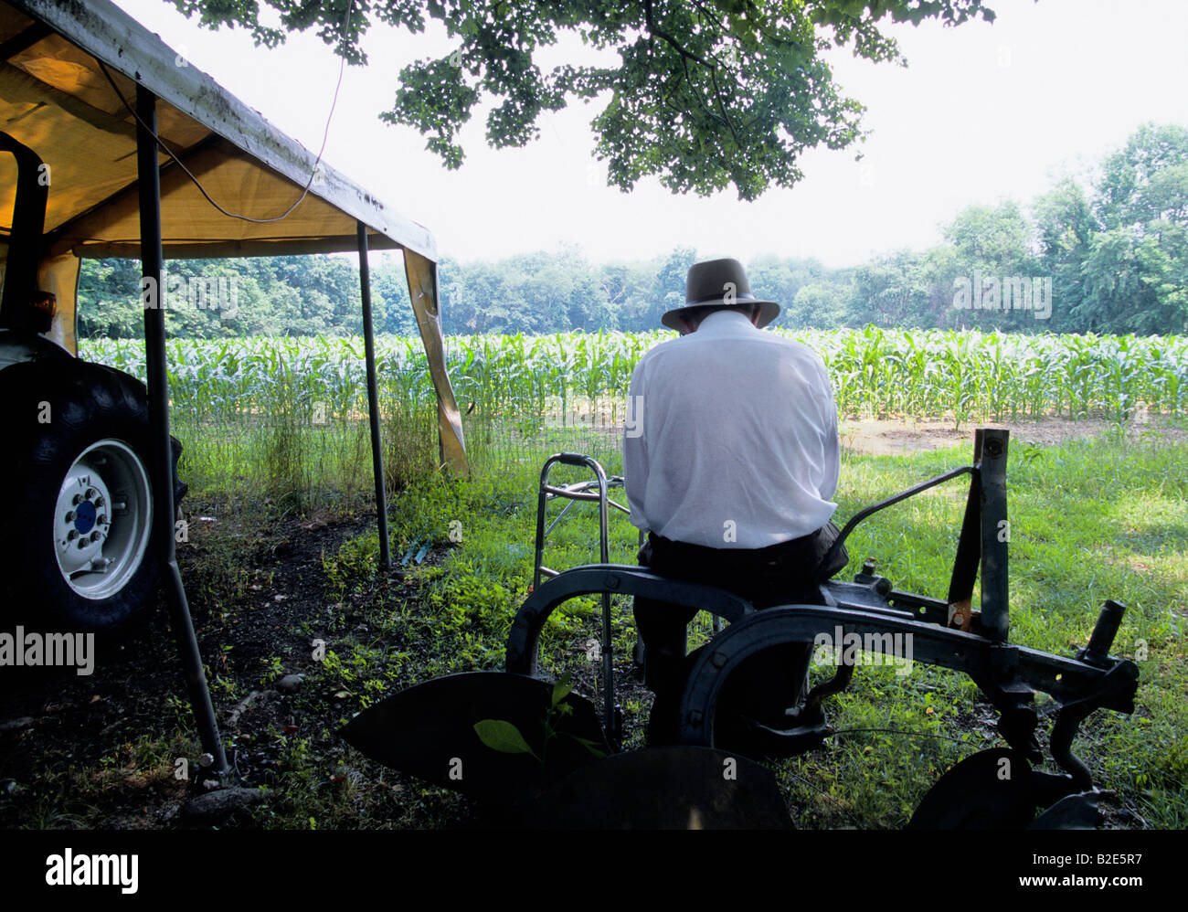 New England tired and disabled farmer sitting on machine part on ...