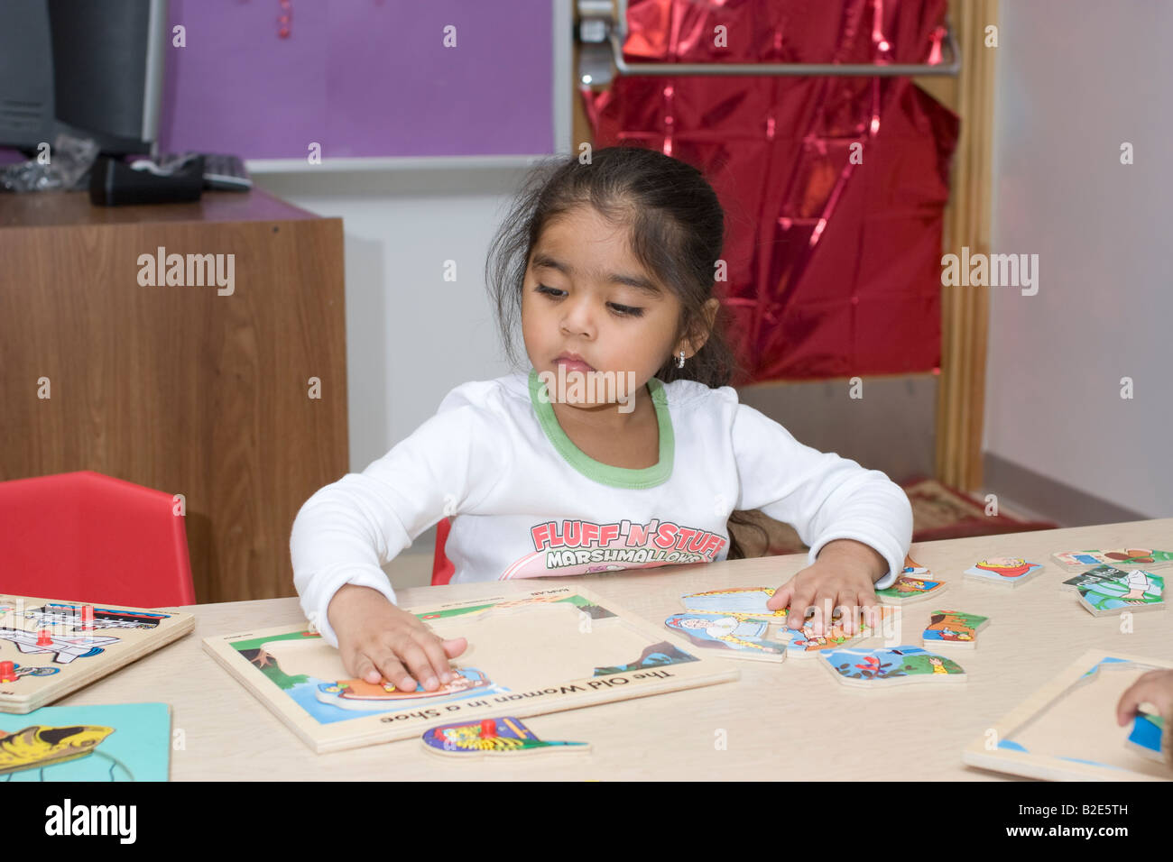 4 year old pre school girl sitting at a table doing a puzzle Stock ...