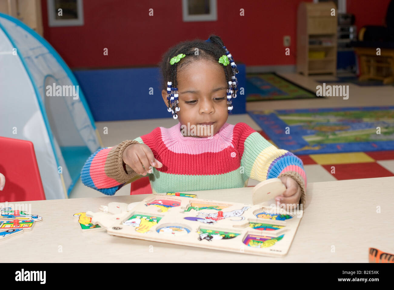4 year old African-American pre school girl sitting at a table doing a ...