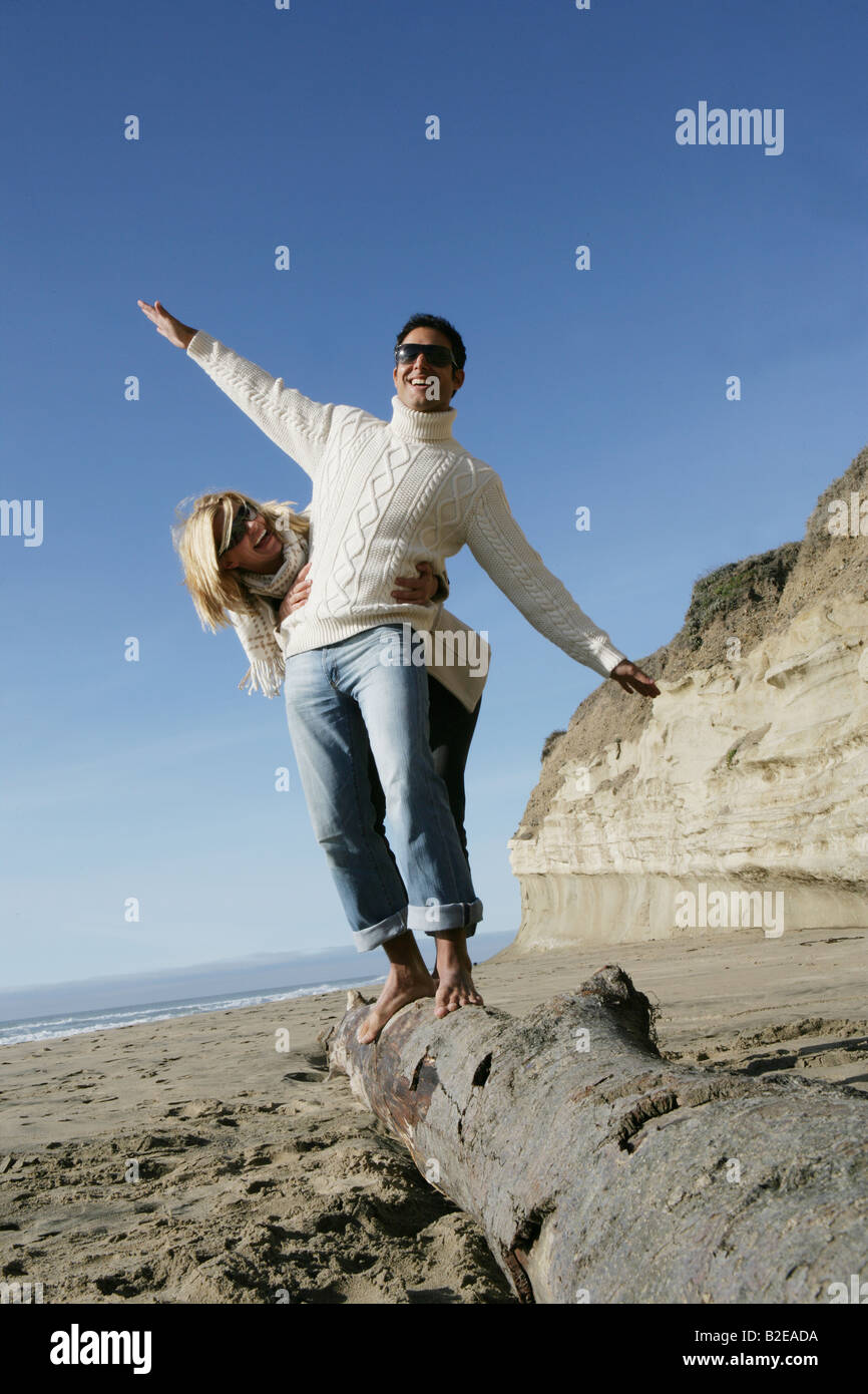 Young couple balancing on log at beach Stock Photo - Alamy
