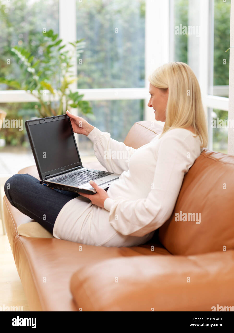 Side profile of woman using laptop on couch Stock Photo - Alamy