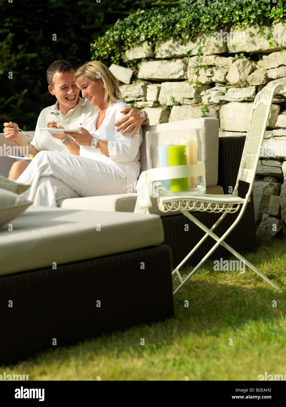 Couple eating food on couch Stock Photo - Alamy