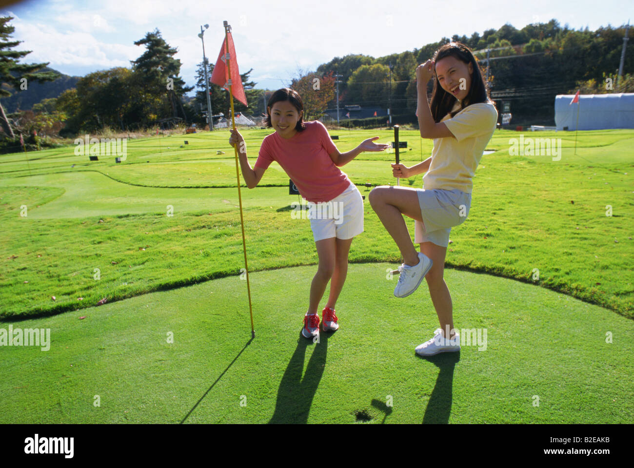 Two young Asian women playing mini golf Stock Photo - Alamy