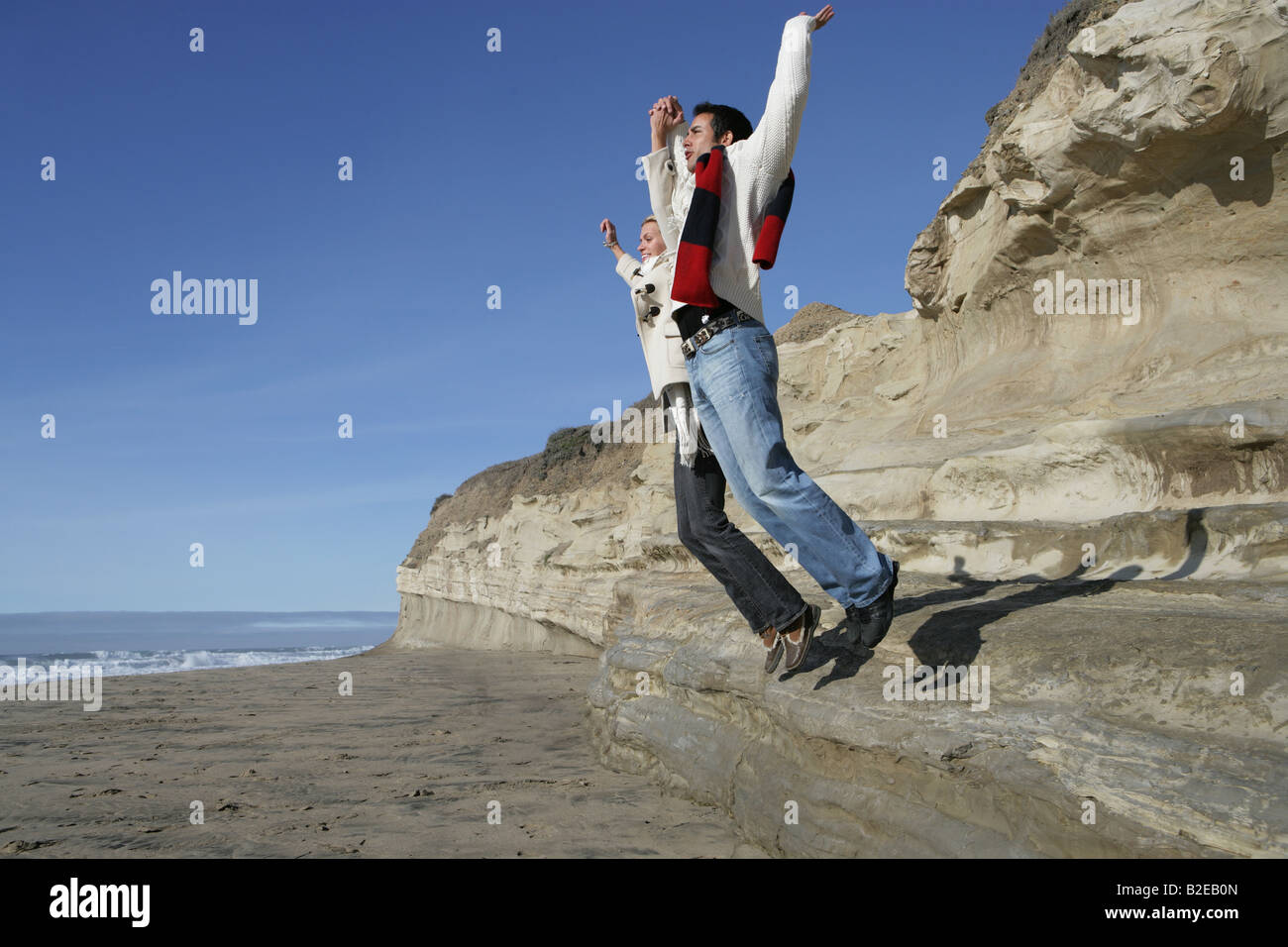 Couple jumping off cliff holding hi-res stock photography and images ...