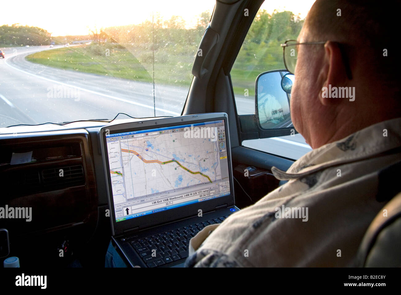 Passenger in a moving vehicle using GPS navigation on a laptop in ...