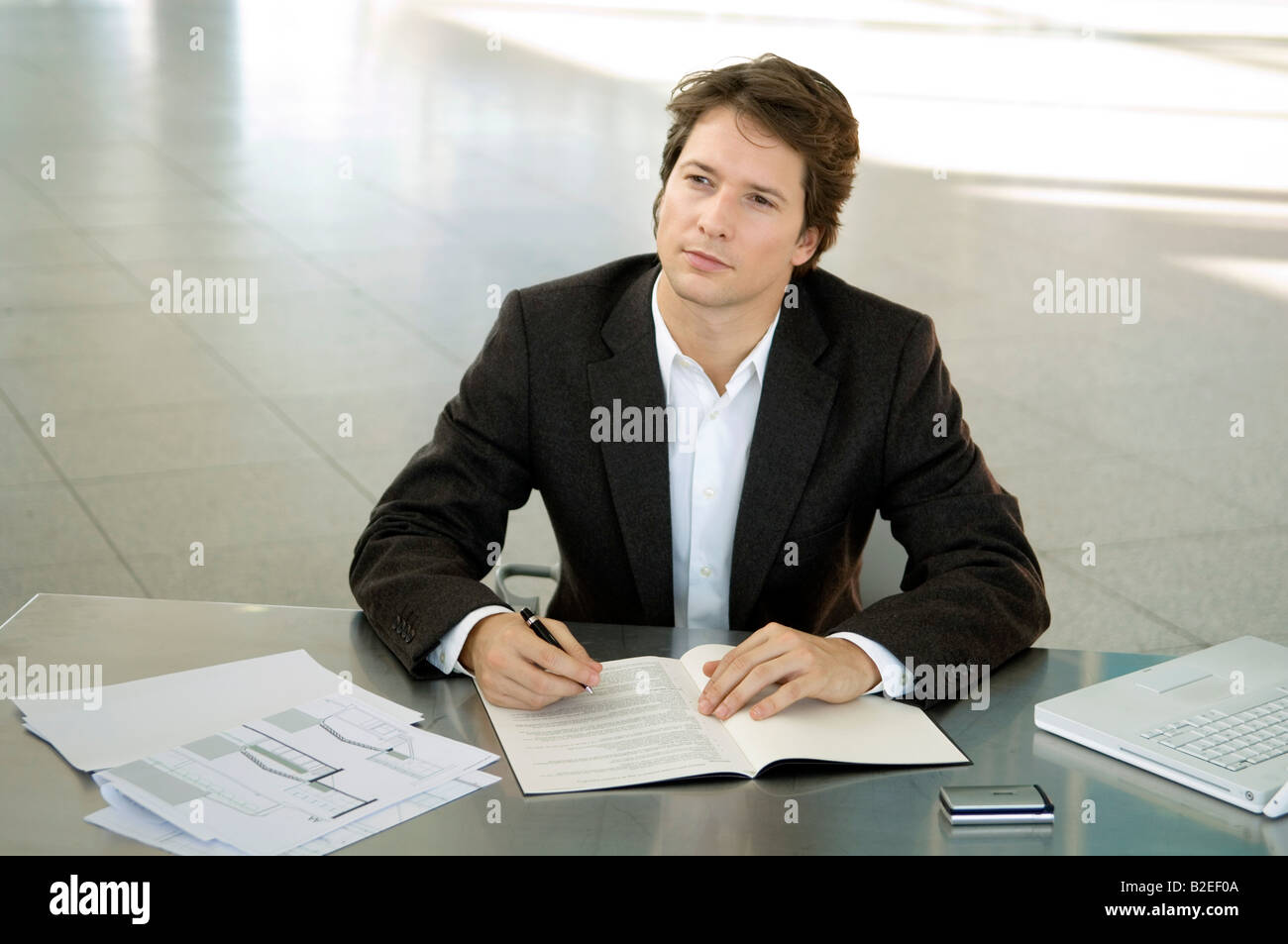 Businessman sitting at a desk and thinking Stock Photo - Alamy