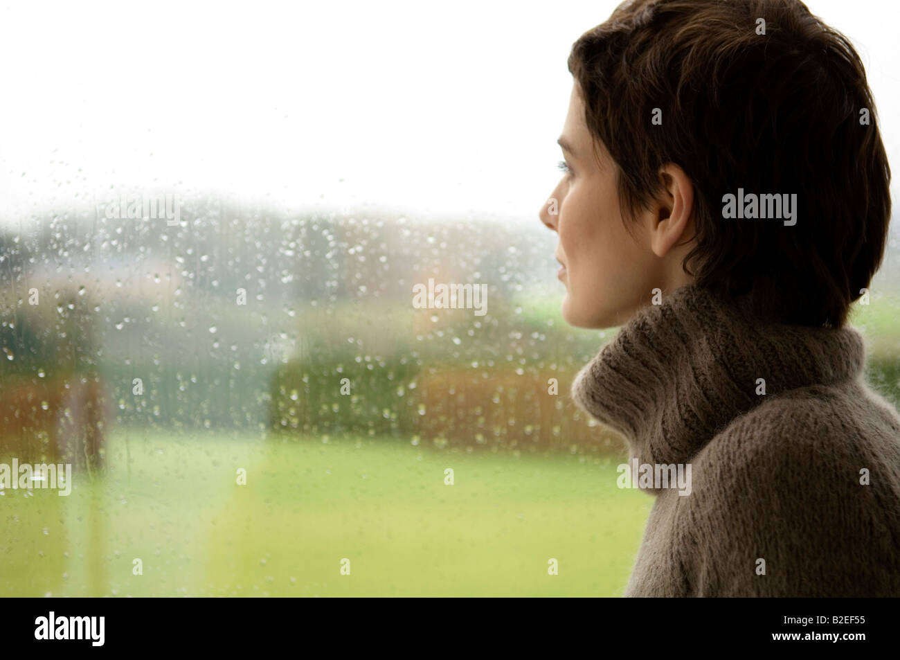 Mid adult woman looking out through a window Stock Photo - Alamy