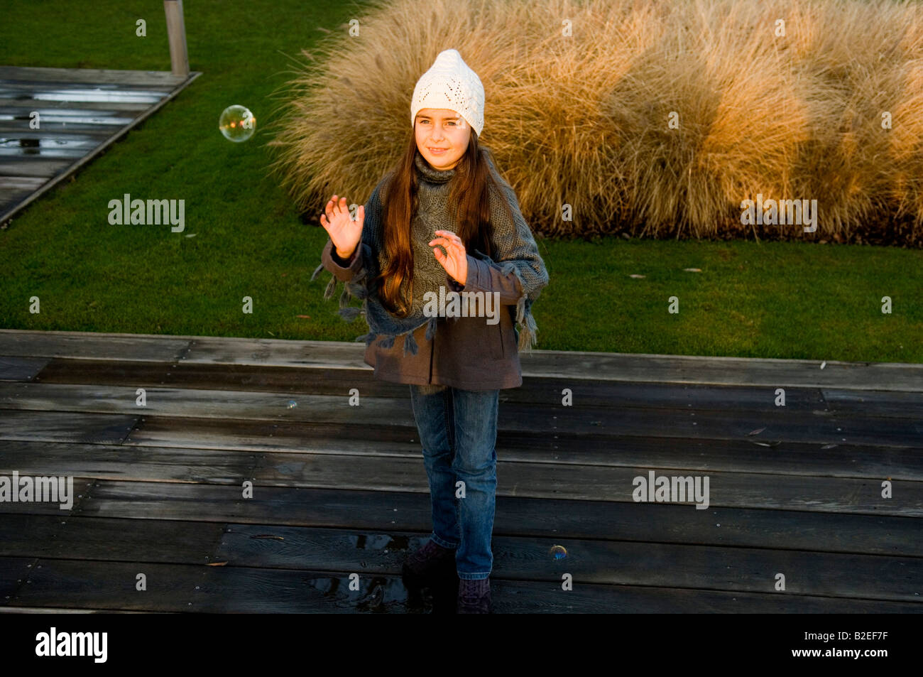 Girl standing on a boardwalk and catching a bubble Stock Photo - Alamy