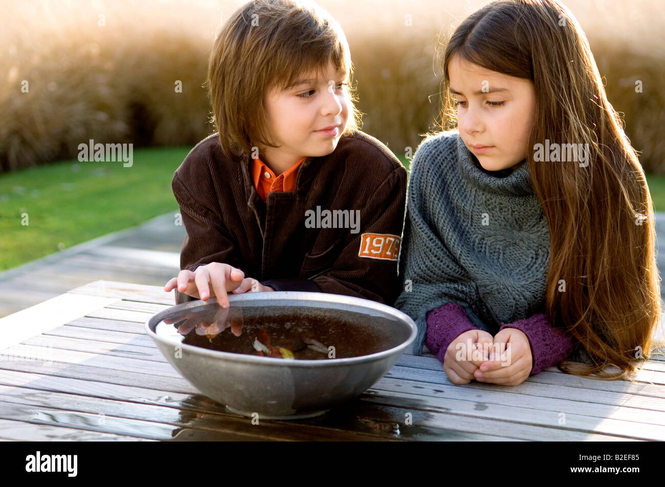 Two children thinking in front of a bowl of water Stock Photo - Alamy