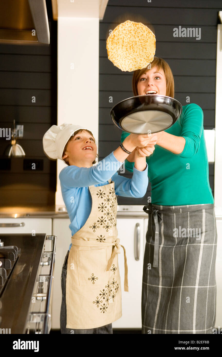 Young woman flipping a pancake with her son Stock Photo - Alamy