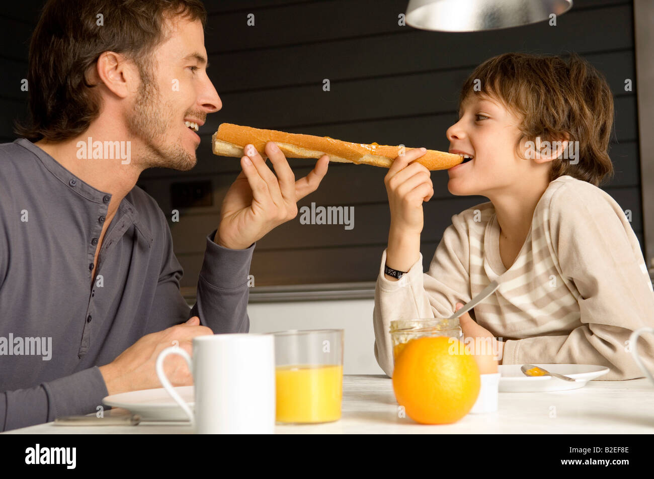 Mid adult man eating a baguette with his son Stock Photo - Alamy