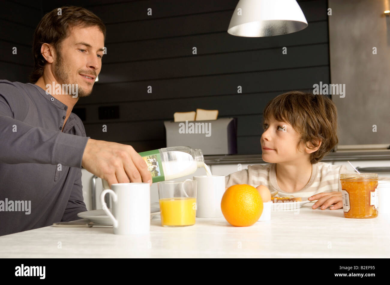 Mid adult man having breakfast with his son in the kitchen Stock Photo ...