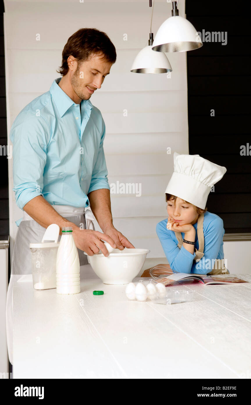 Mid adult man making a cake and his son in the kitchen Stock Photo - Alamy