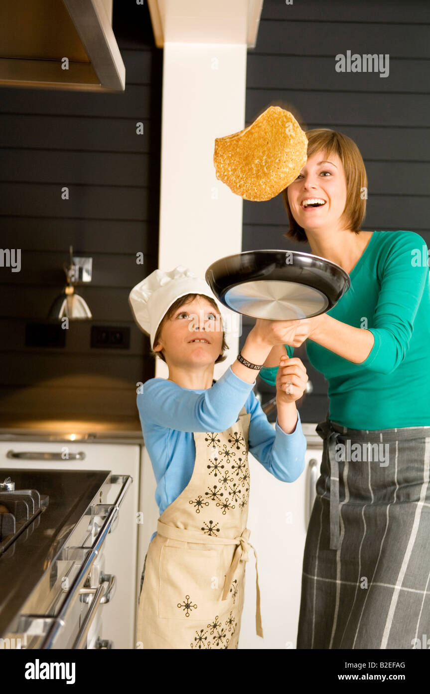 Young woman flipping a pancake with her son Stock Photo - Alamy