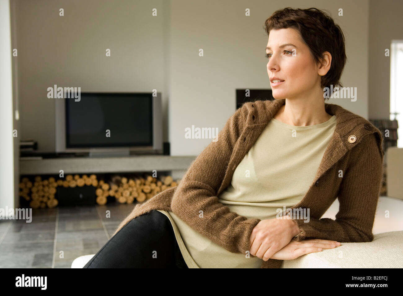 Mid adult woman leaning against a couch Stock Photo - Alamy