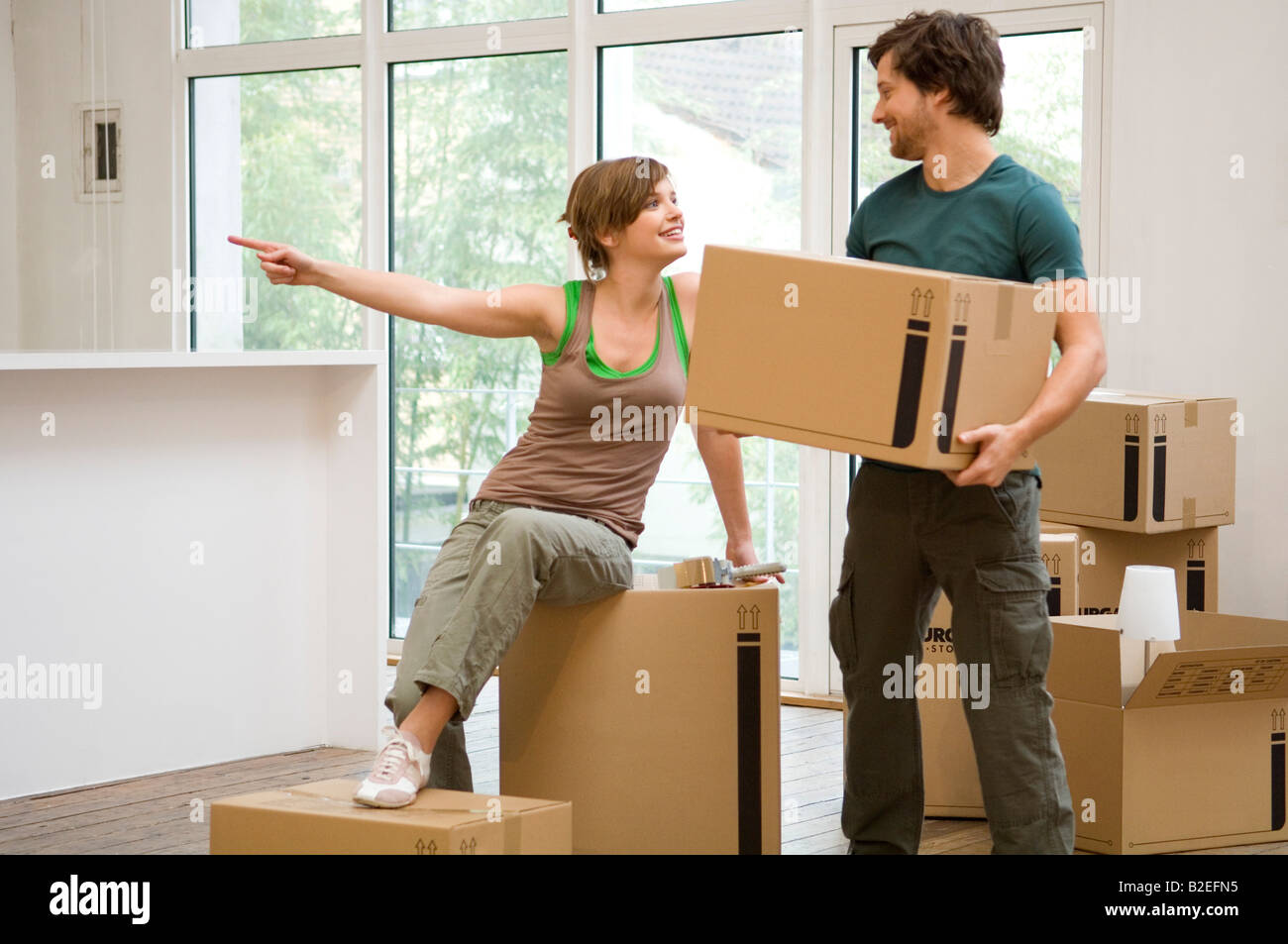 Mid adult man holding a cardboard box and a young woman pointing away ...