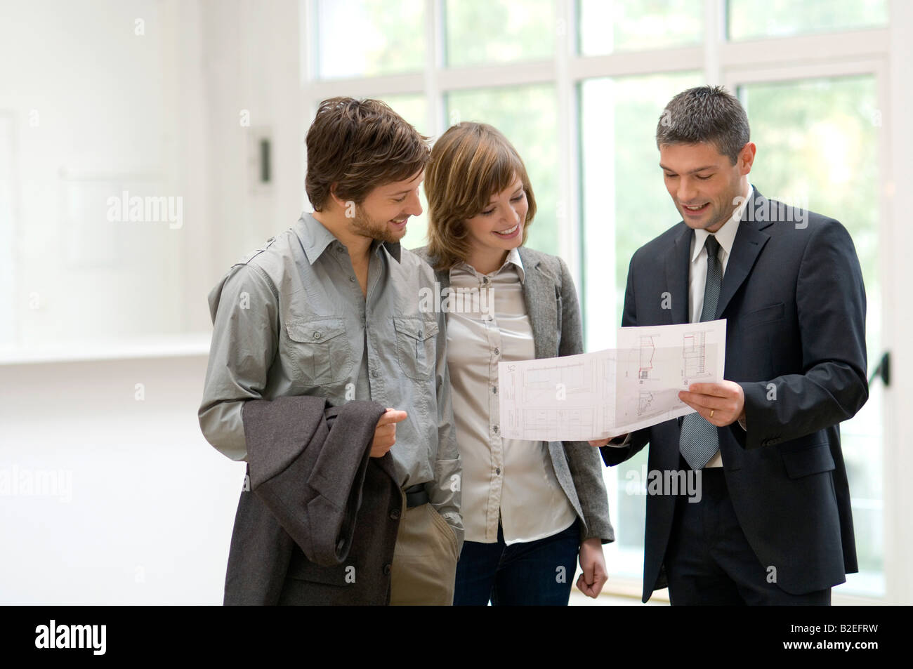 Real estate agent showing a blueprint to a couple Stock Photo - Alamy